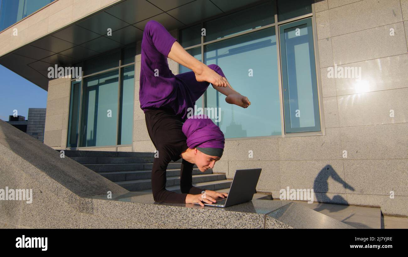Strong acrobat business woman funny muslim girl in hijab stands on ...
