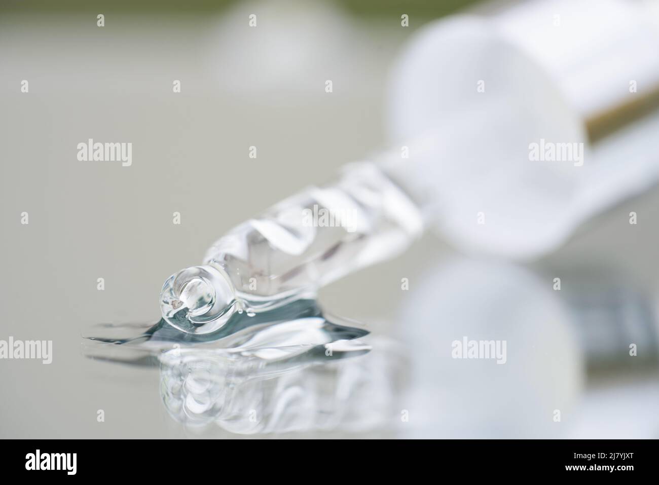 Glass dropper with transparent liquid on glass background with copy ...