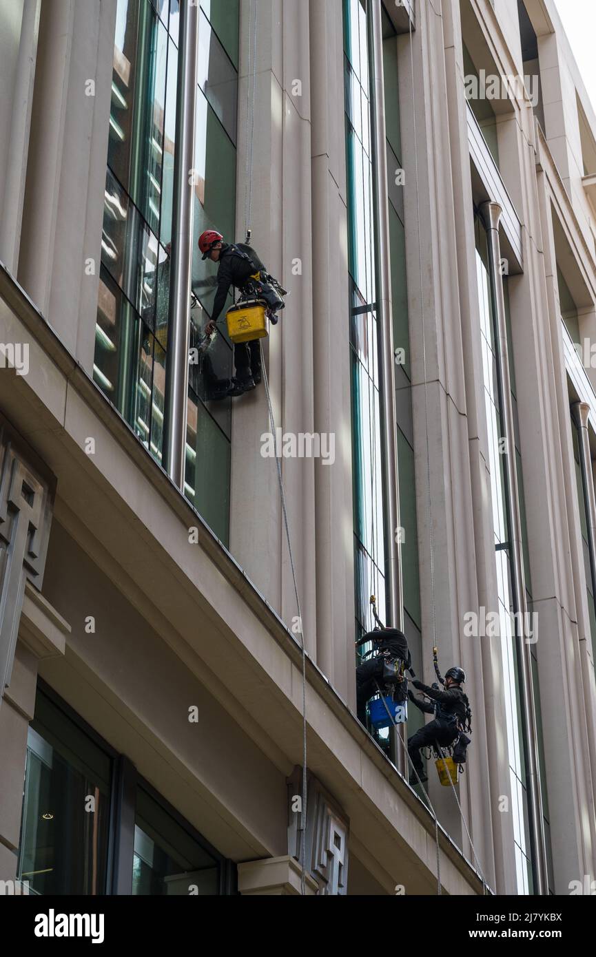 Abseiling window cleaners working on an office building. London ...