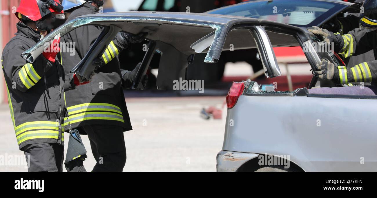 firefighters as they remove the hood of a car damaged after the road ...