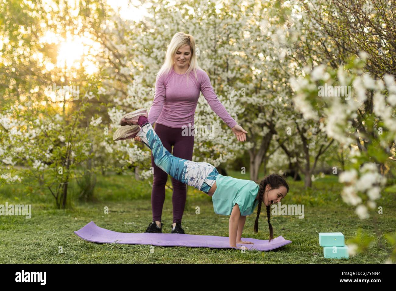 Young sports mother doing physics exercise outdoors in garden near her ...