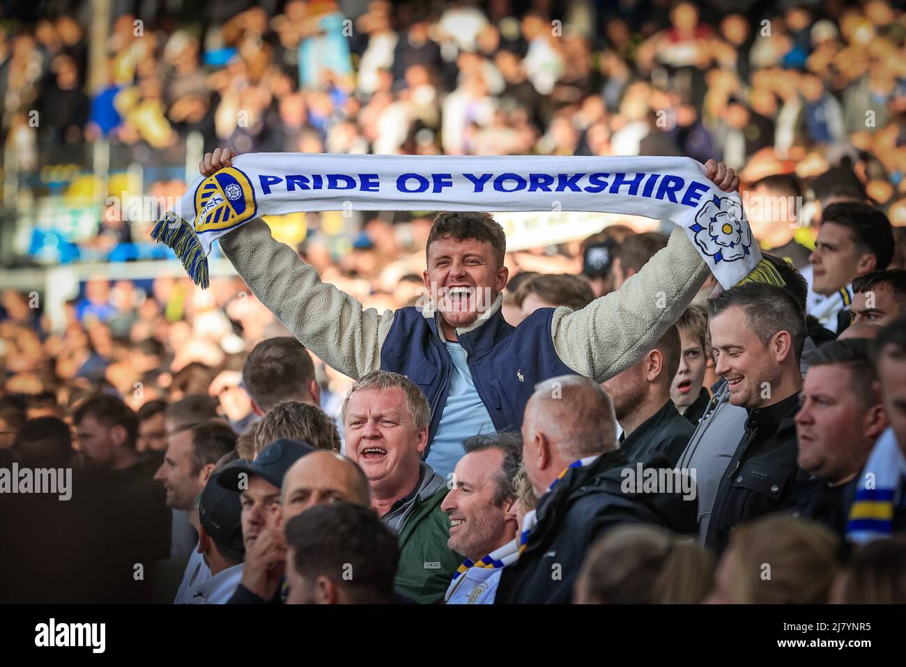 A Leeds United fan holds his scarf up high as all the crowd sing ...