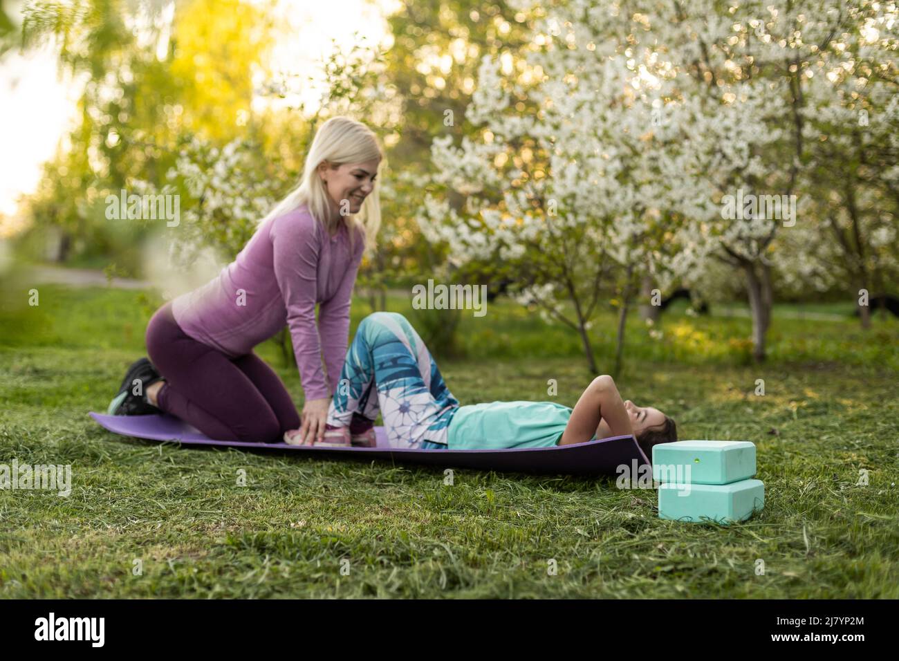Young sports mother doing physics exercise outdoors in garden near her ...