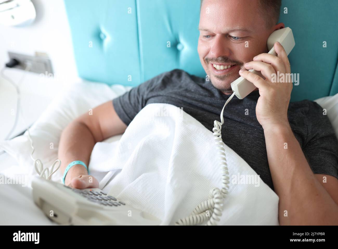 Smiling man calling on reception in hotel, want to order lunch in room ...