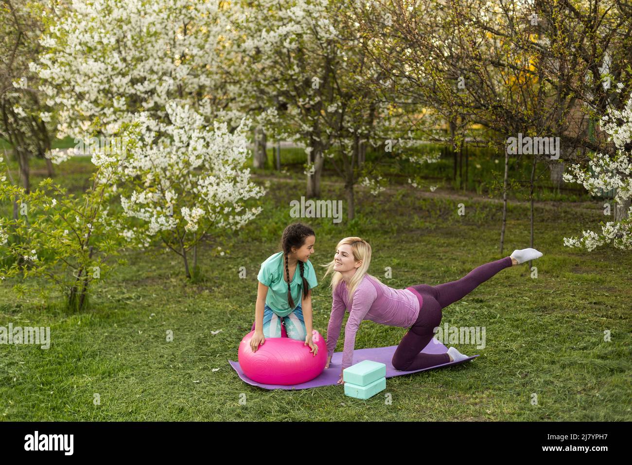 Young sports mother doing physics exercise outdoors in garden near her ...