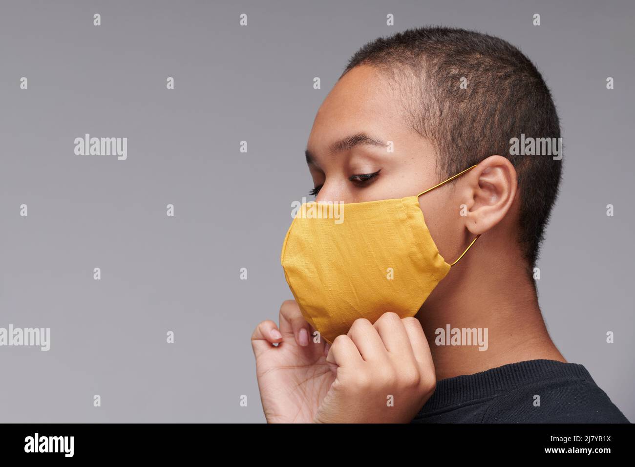 Side view of hipster black girl with buzz cut covering nose and mouth ...
