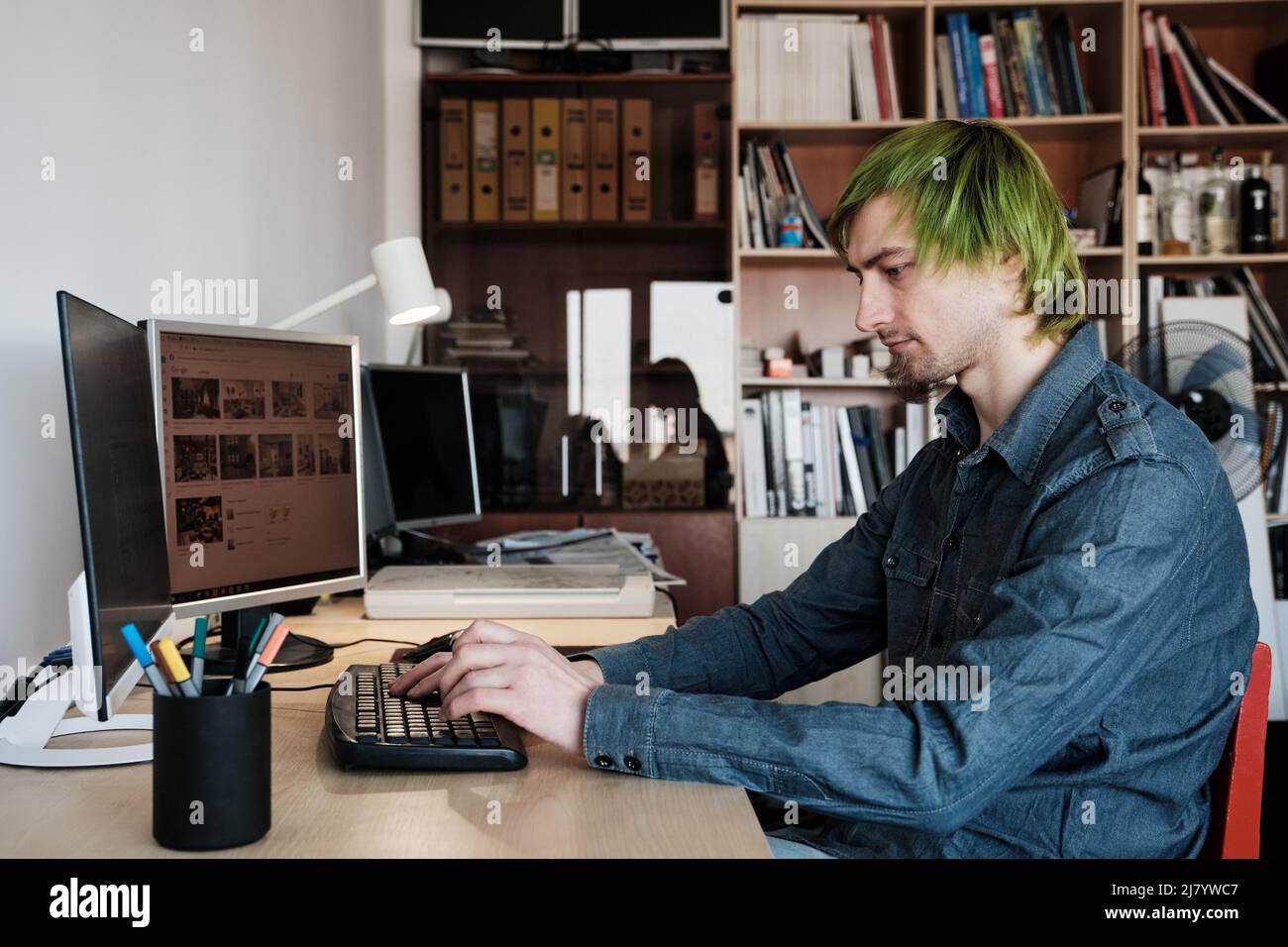 Designer in denim shirt working in office. Man working at the computer ...
