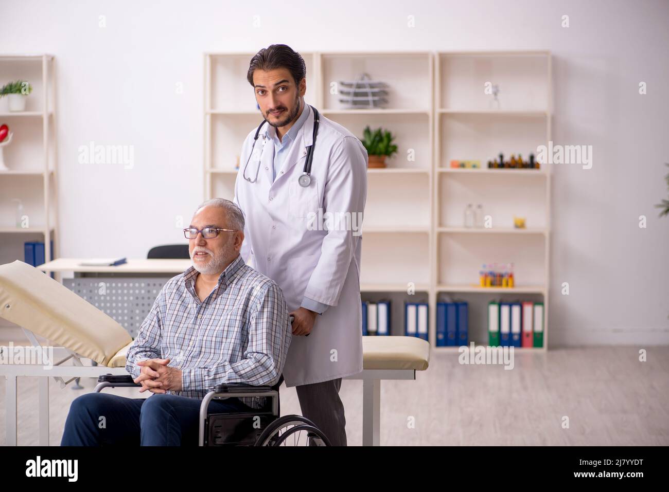 Old male patient in wheelchair visiting young male doctor Stock Photo ...