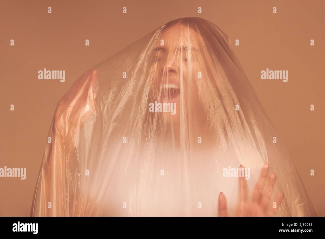 Emotional young woman screaming inside of plastic bag while feeling ...