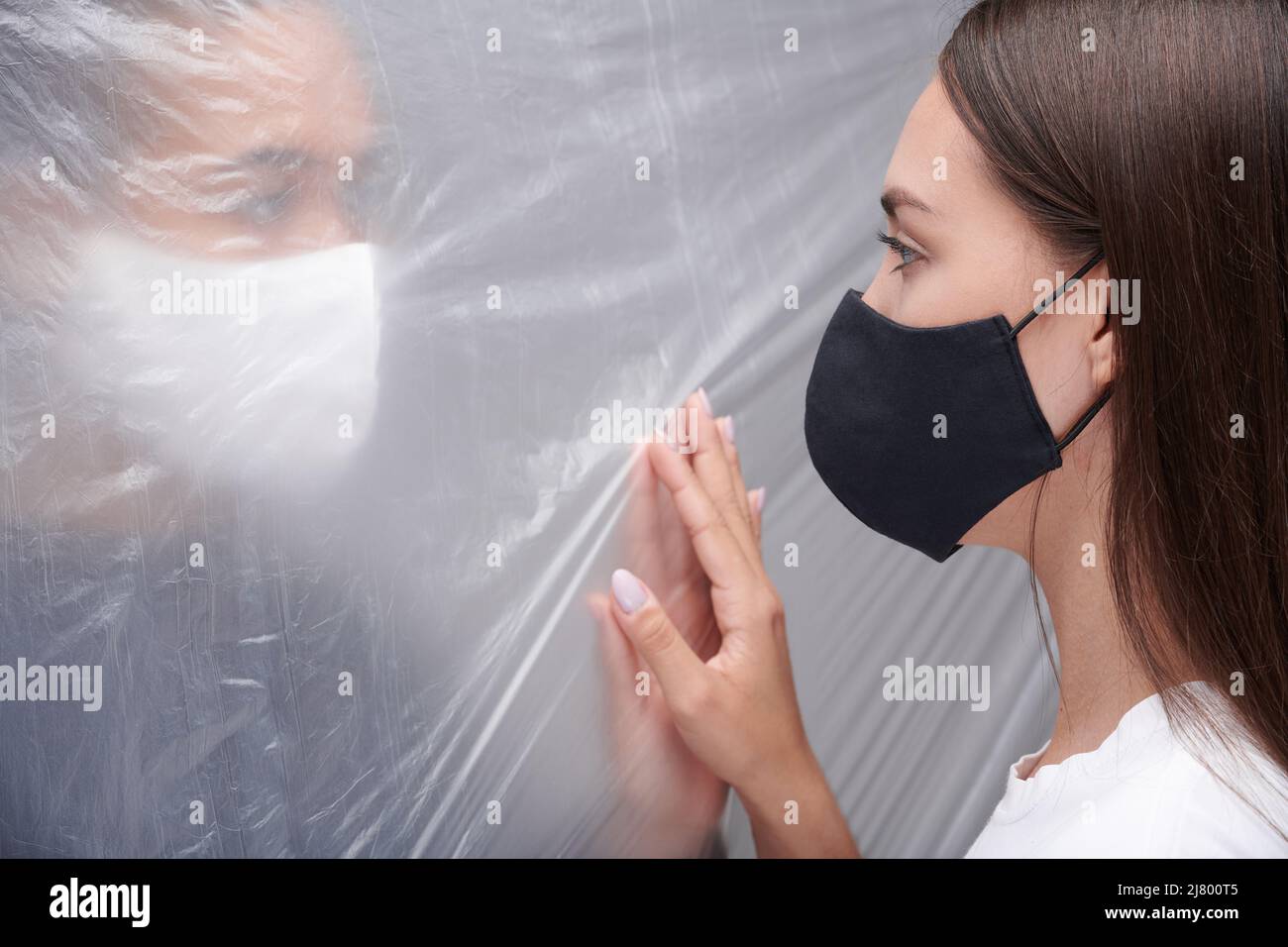 Young multi-ethnic women in cloth masks touching through polyethylene ...