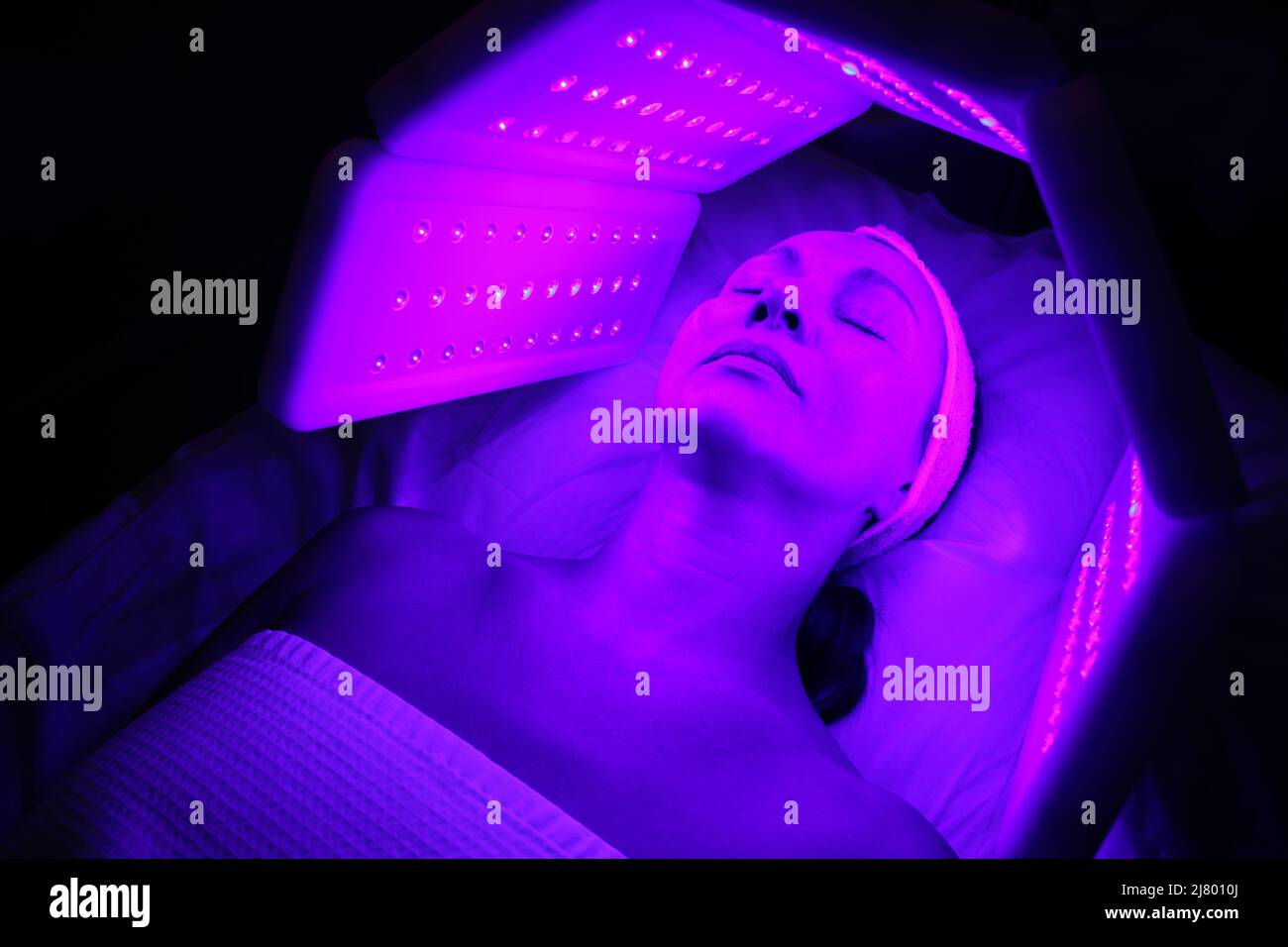 An elderly woman undergoes a facial rejuvenation procedure. Woman face ...