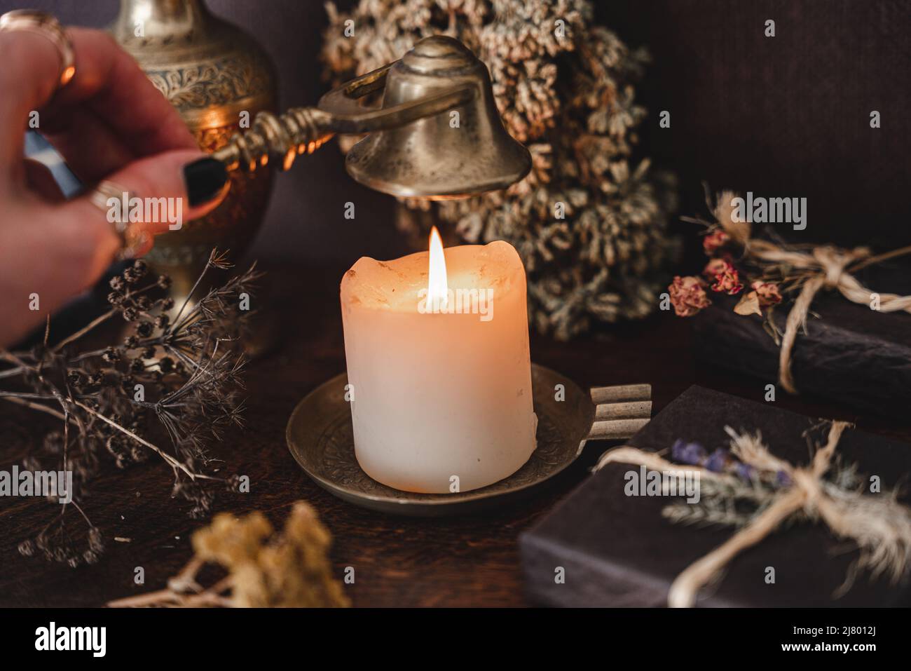 Wiccan witch putting out a white candle flame with antique brass gold ...