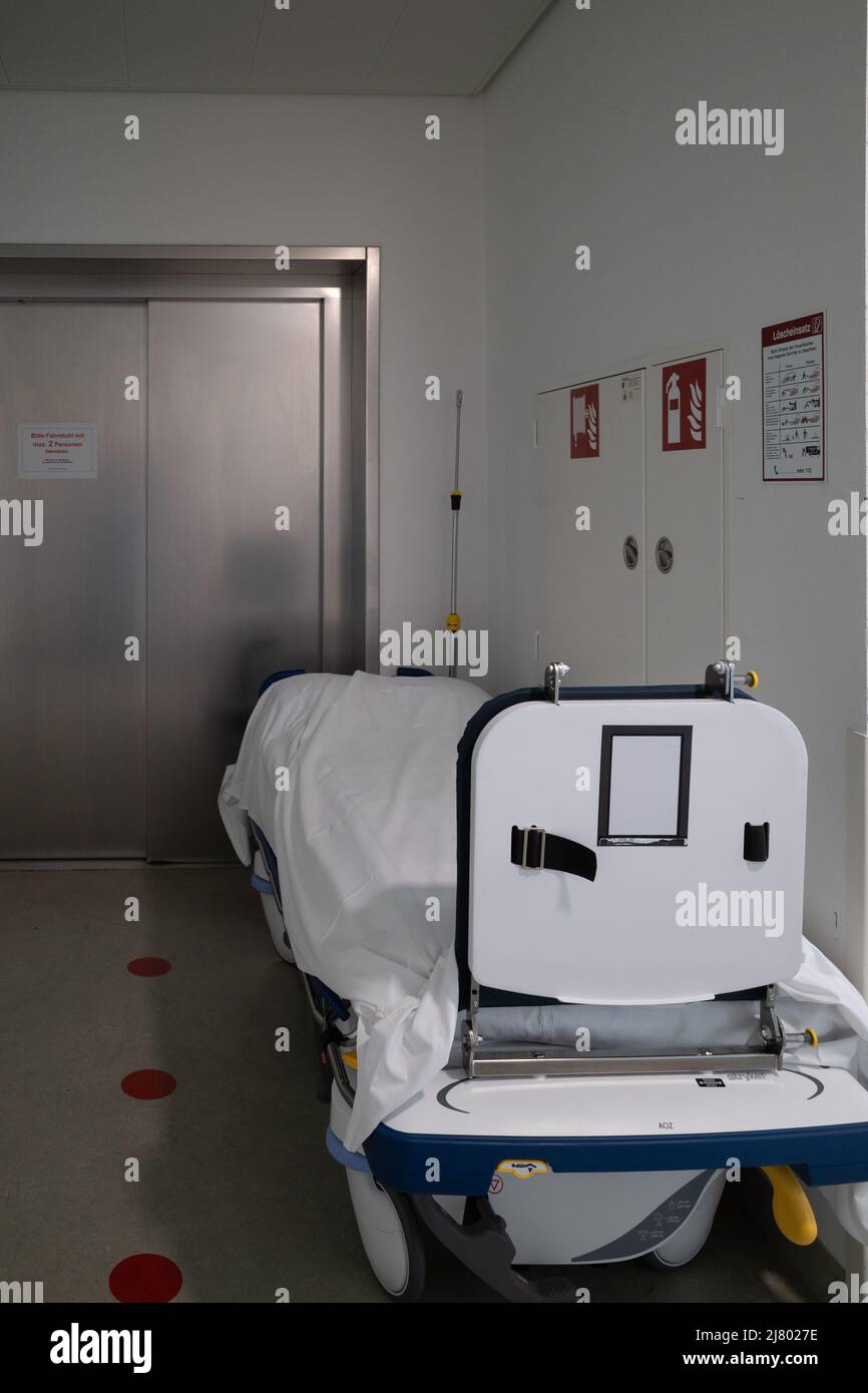 a patient transport bed stands in front of an elevator in a hospital ...