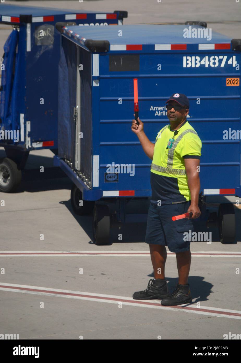 A ground crew member helps direct an American Airlines plane to its ...
