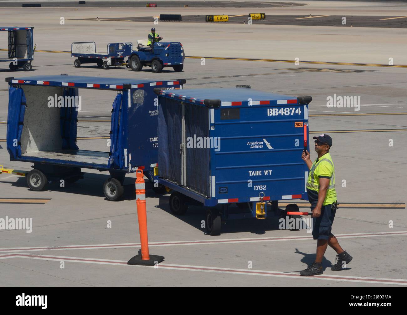 A ground crew member helps direct an American Airlines plane to its ...