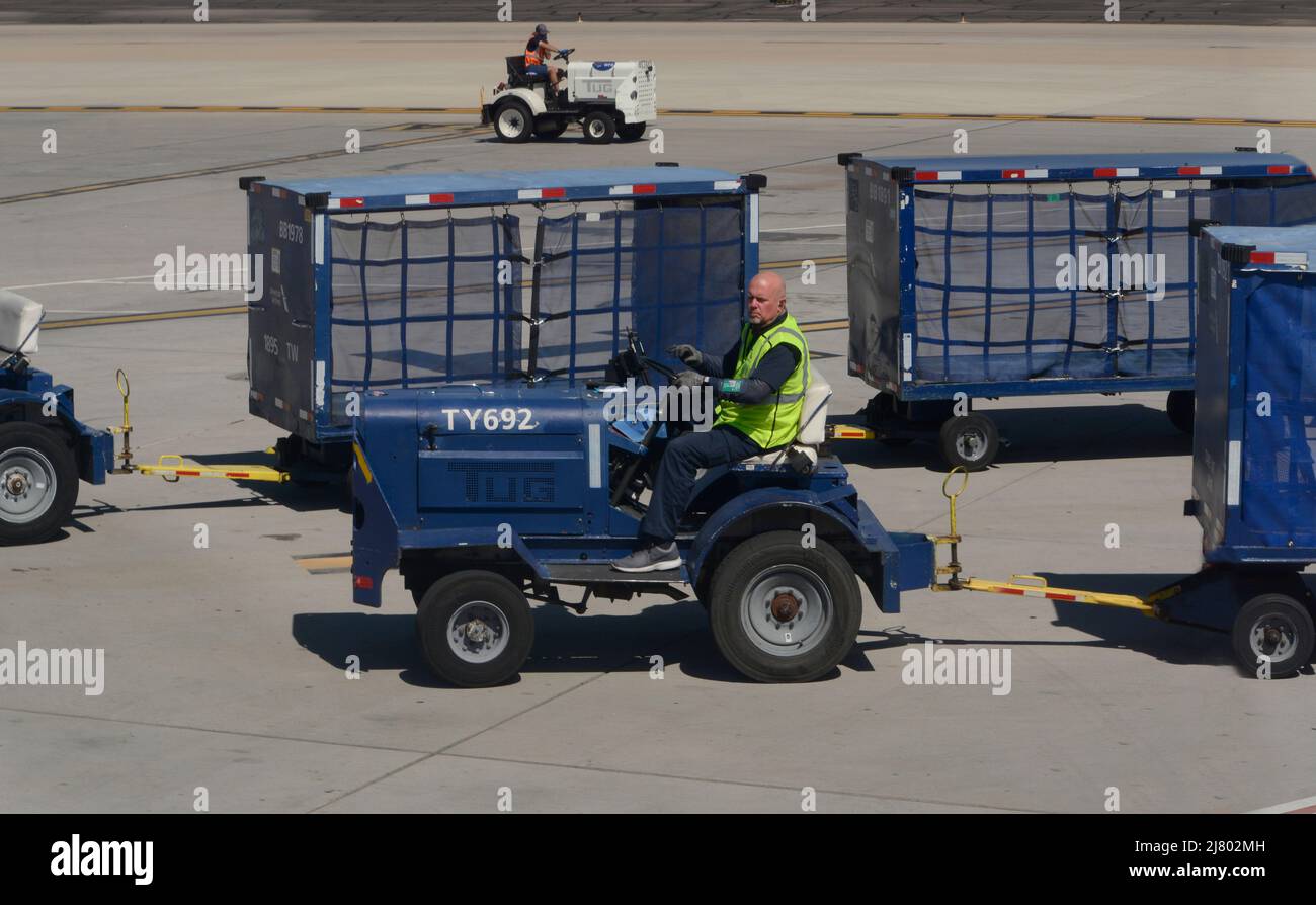 A ground crew worker transports passenger baggage from an aircraft to ...