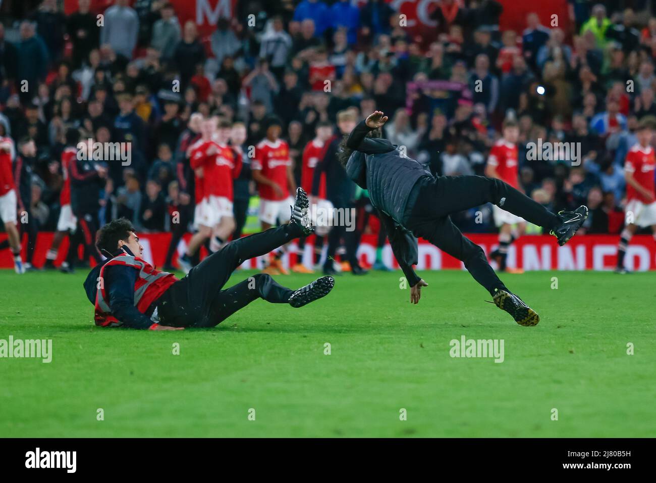 A pitch invader is slide tackled to the floor by a steward after the ...