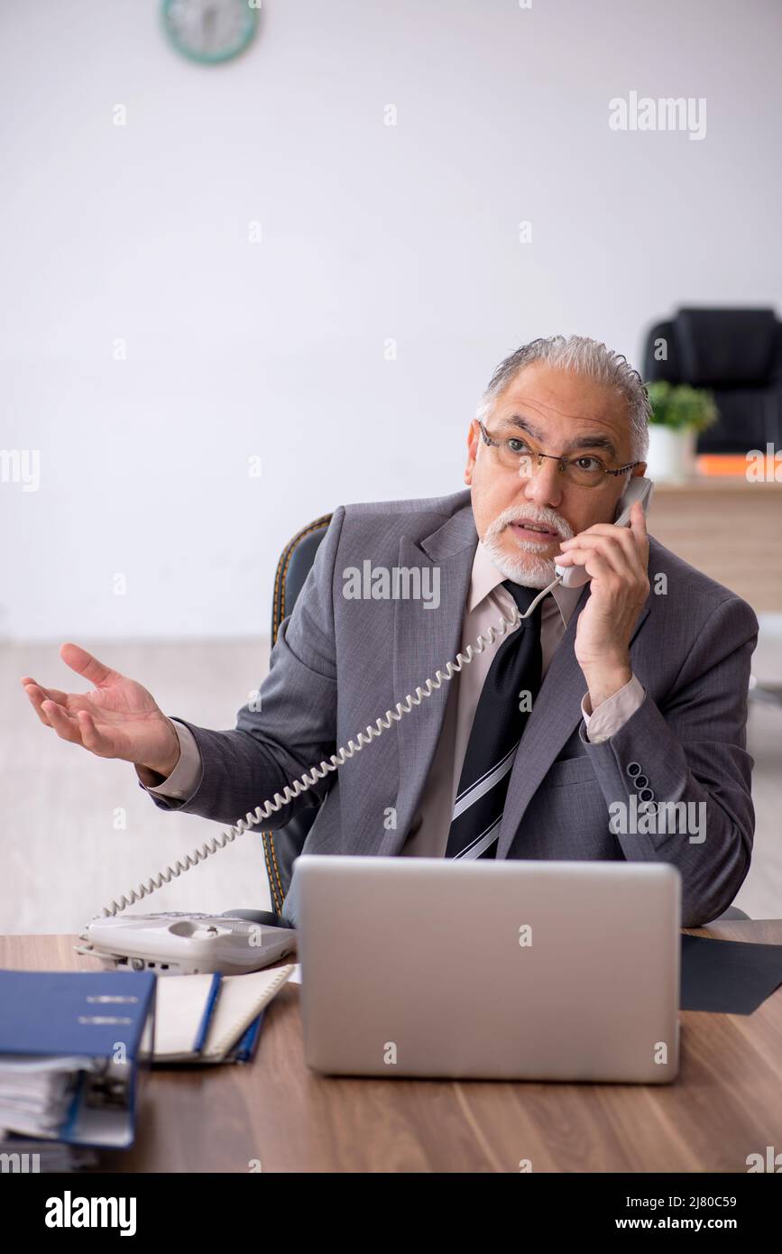 Old male boss sitting at workplace Stock Photo - Alamy