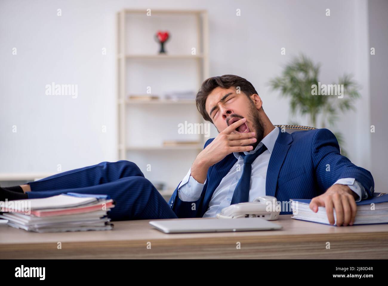 Young businessman employee extremely tired at workplace Stock Photo - Alamy