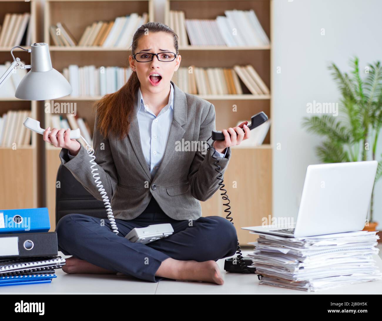 The busy angry businesswoman sitting on the desk in office Stock Photo ...