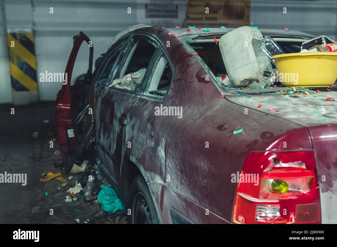 devastated car full of trash in the underground parking lot. High ...