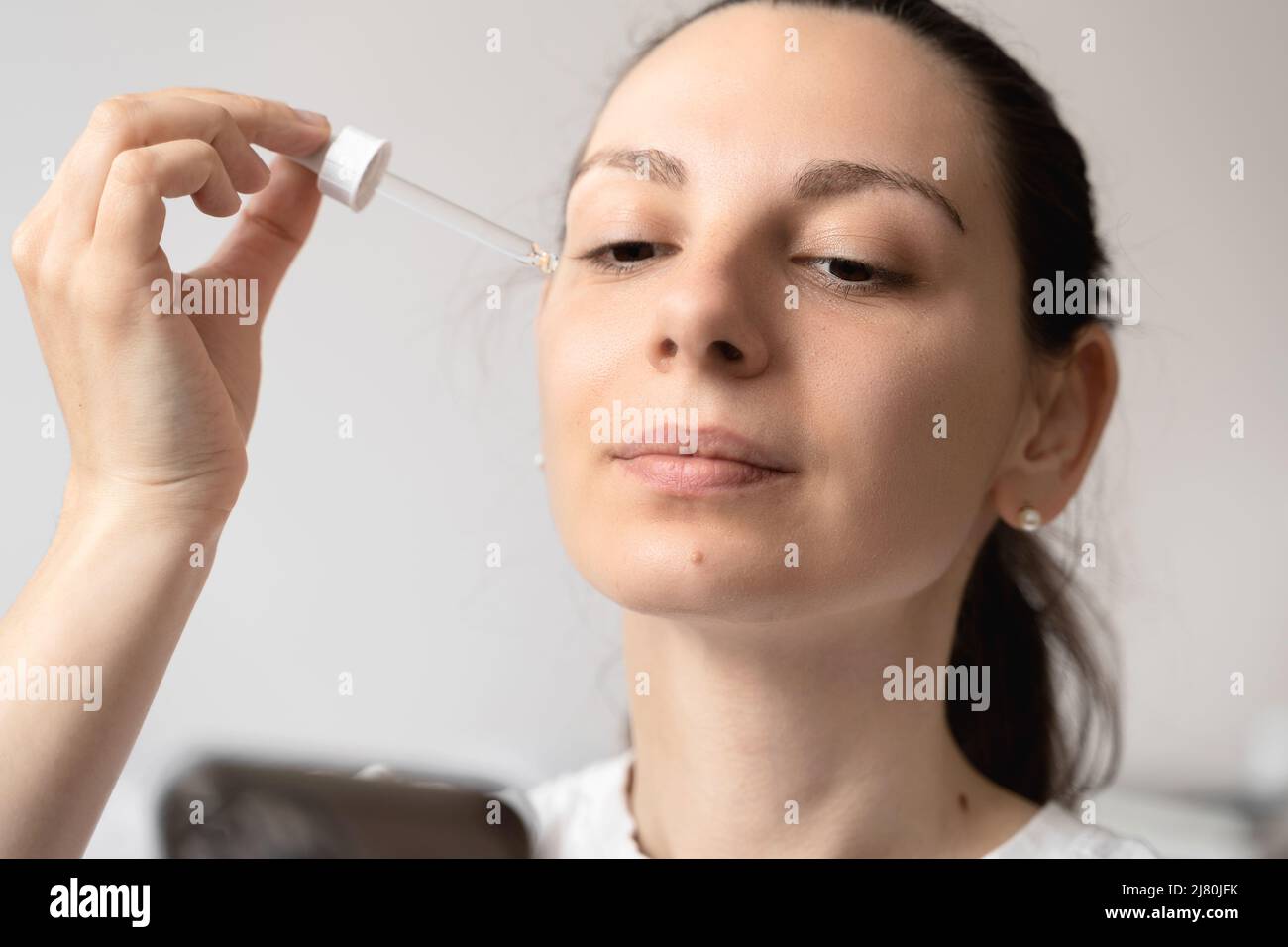 Close up of white woman hand applying oil of essential oil or serum for ...