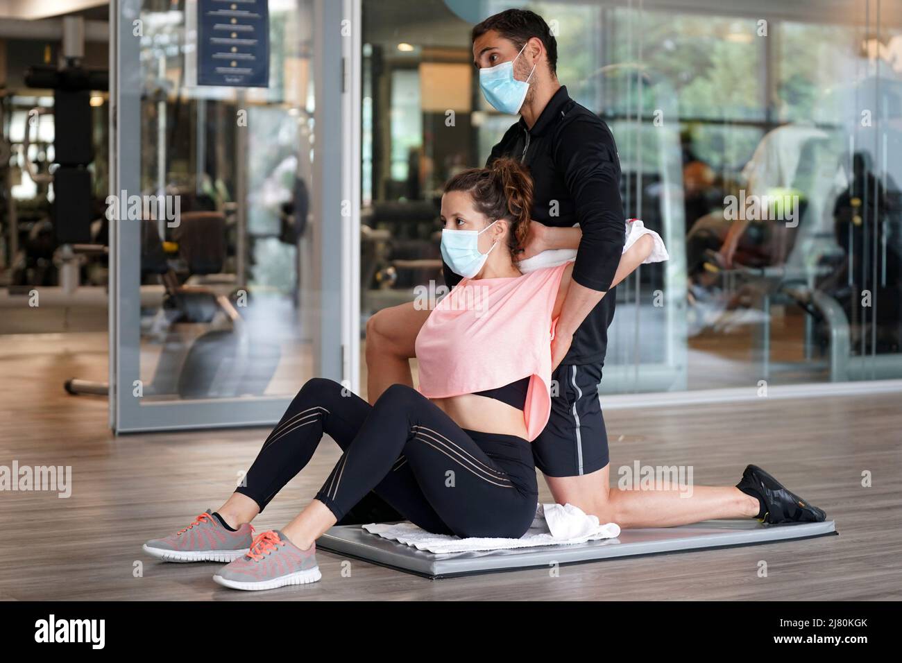 Personal trainer in the gym helping a client do stretching exercises ...