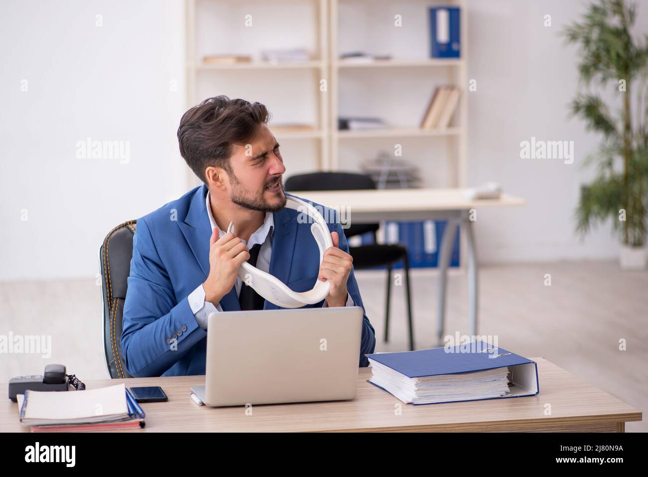 Young neck injured businessman employee at workplace Stock Photo - Alamy