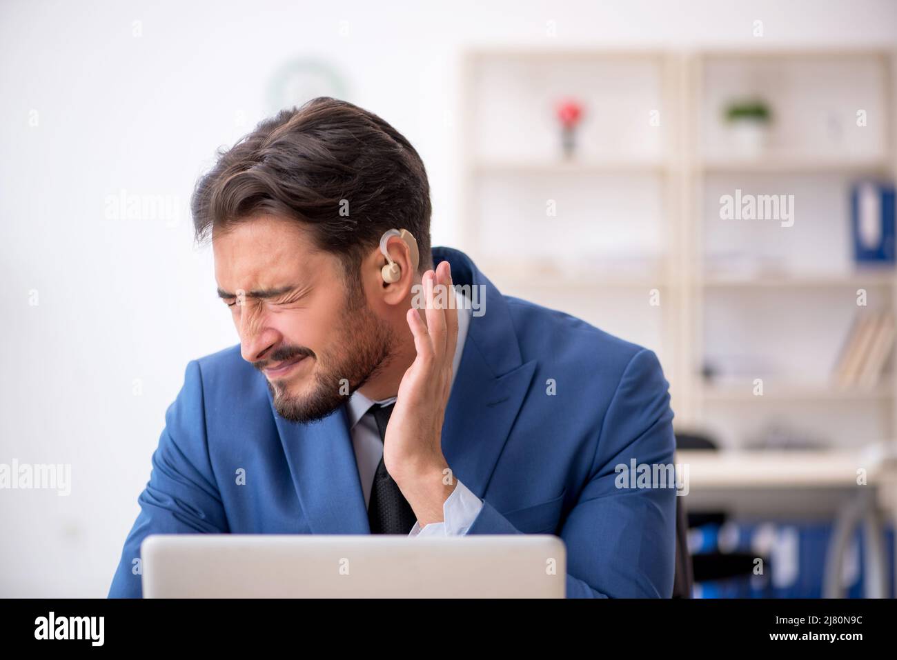 Deaf businessman employee using hearing aid in the office Stock Photo ...