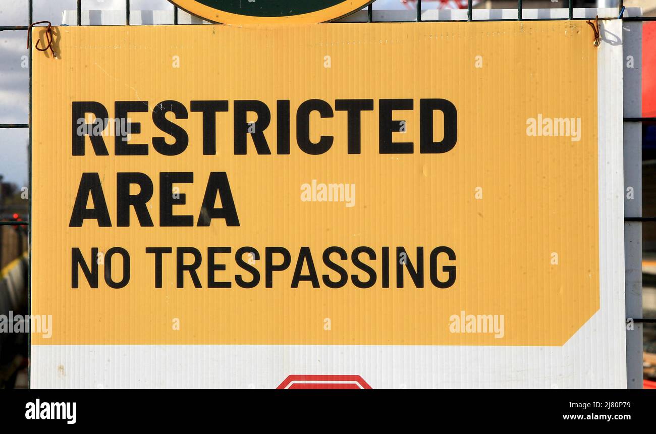 Yellow "Restricted Area No Trespassing" sign on chain link fence Stock ...