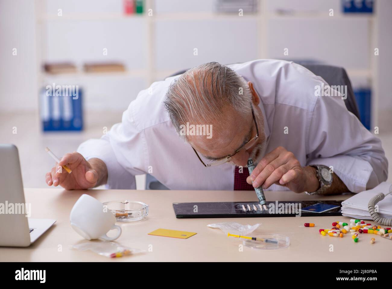 Old male drug addicted employee sitting at workplace Stock Photo - Alamy