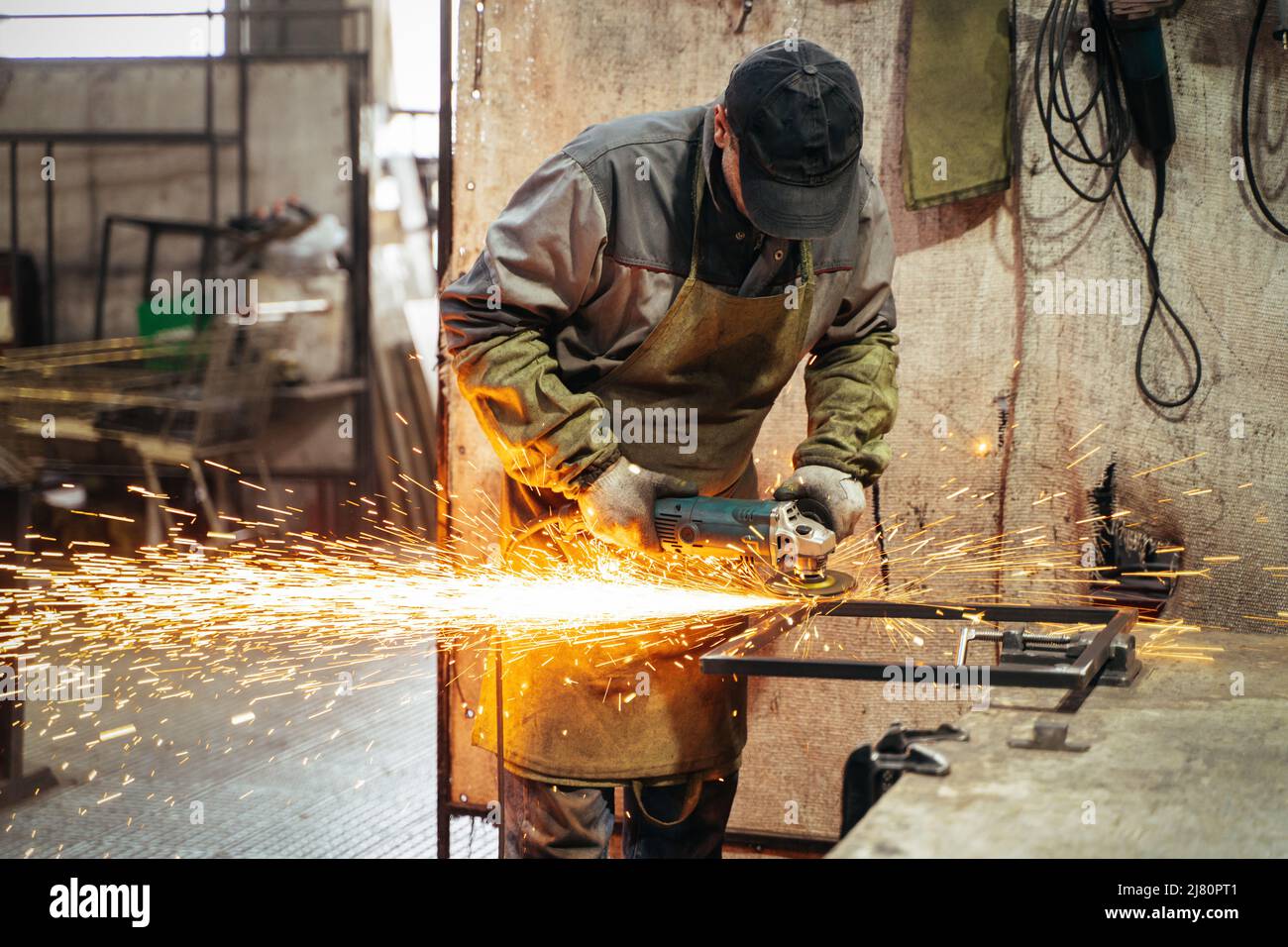 Locksmith in special clothes and goggles works in production. Metal ...