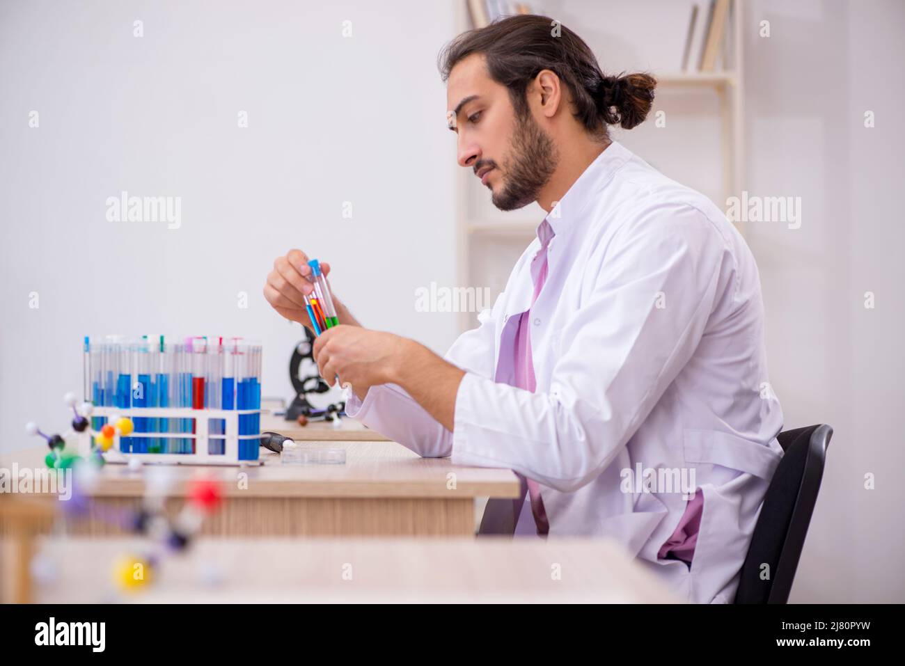 Young chemist sitting at the desk in the classroom Stock Photo - Alamy