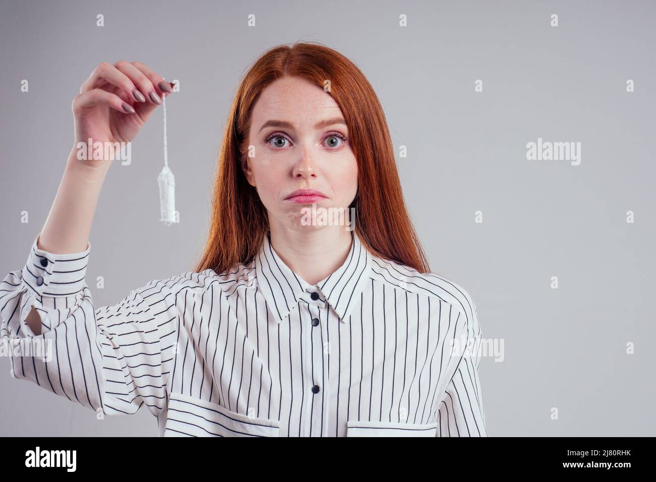Closeup photo of young redhead businesswoman in striped shirt holding ...