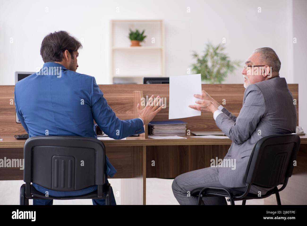 Two male employees working at workplace Stock Photo - Alamy