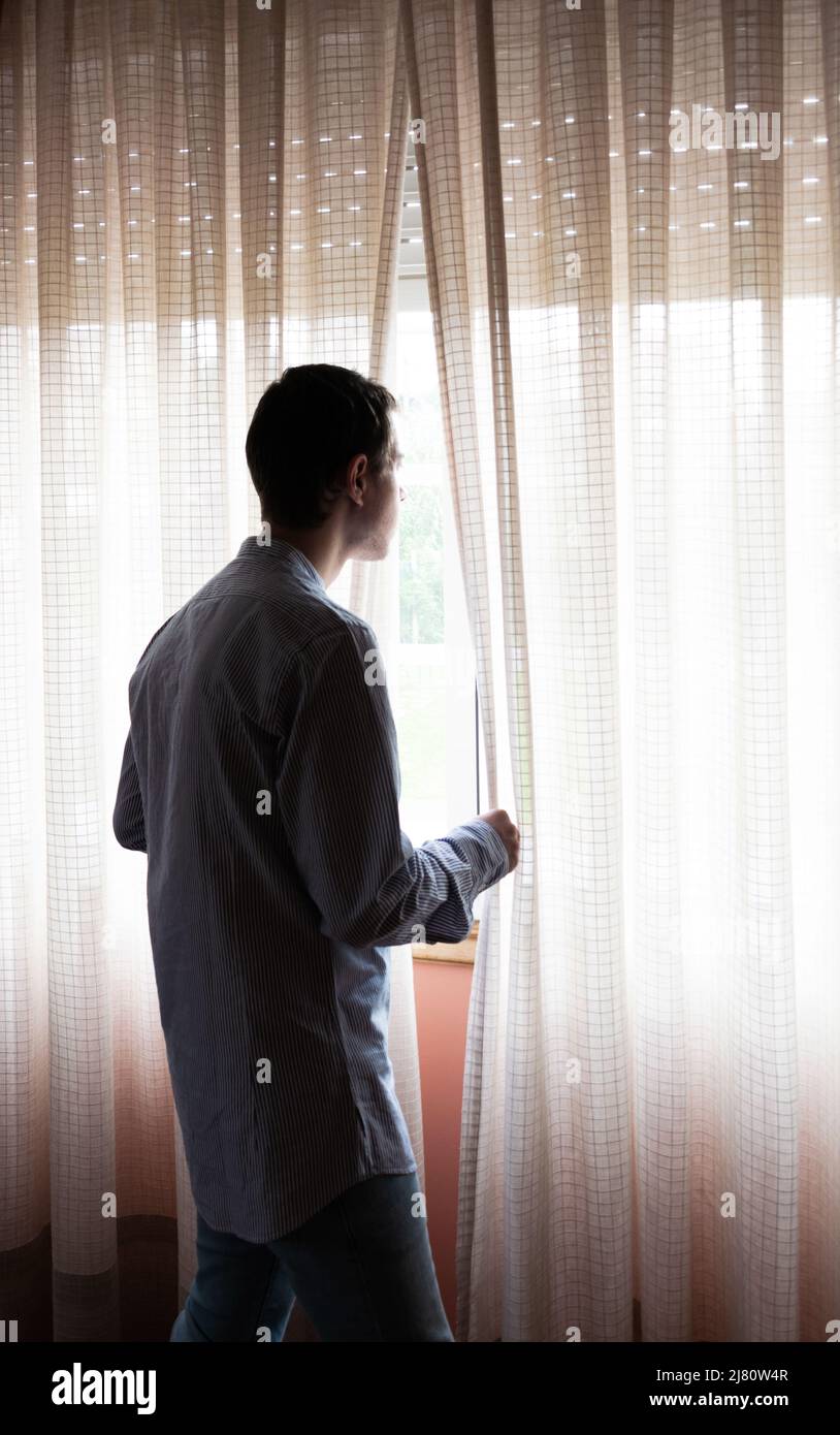 Rear view of a man looking through a window Stock Photo - Alamy