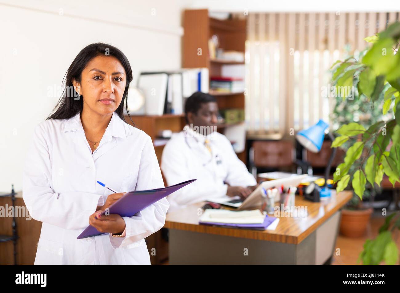 Polite female doctor filling out medical form at clipboard Stock Photo ...