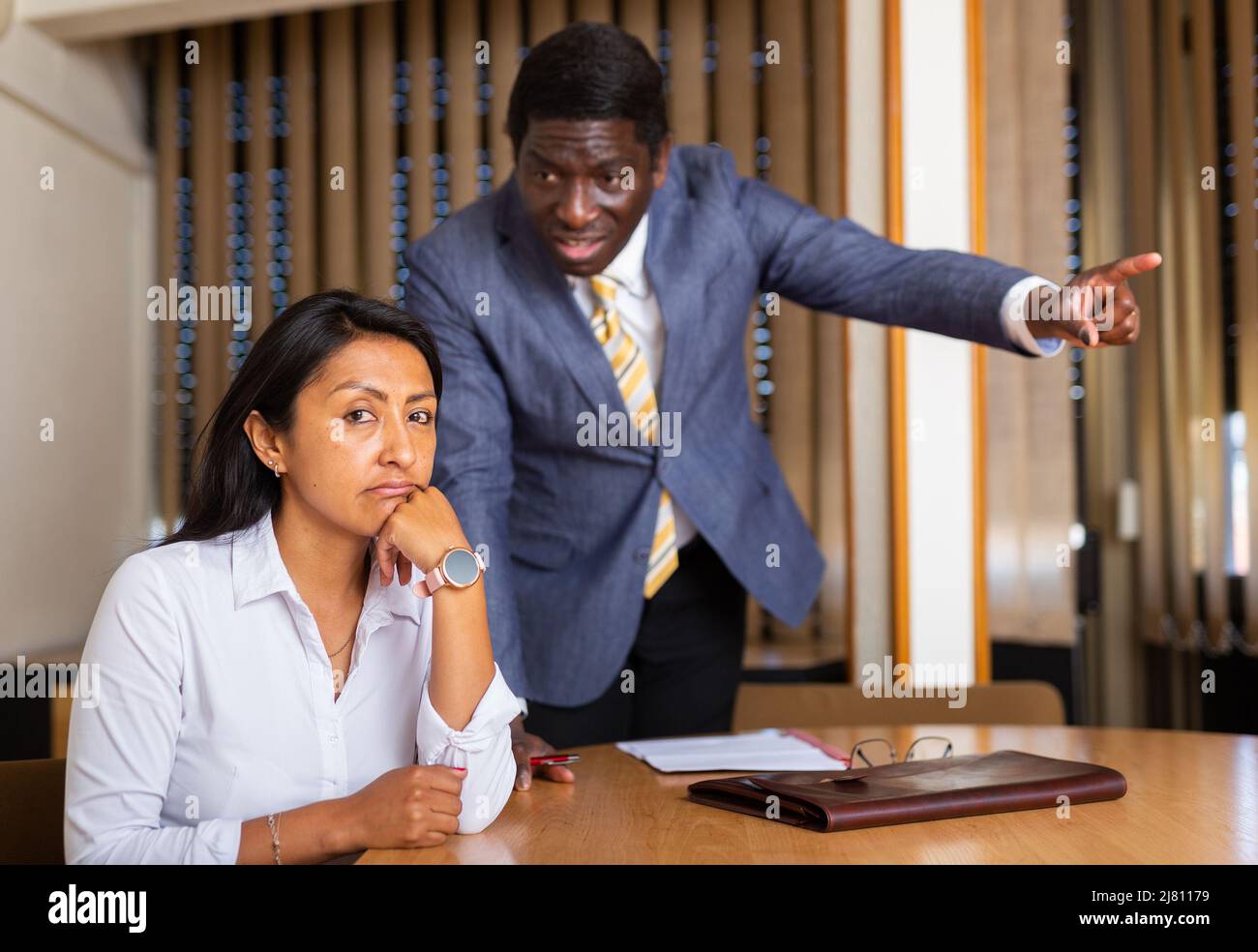 Upset woman sitting in office with disgruntled boss behind Stock Photo ...