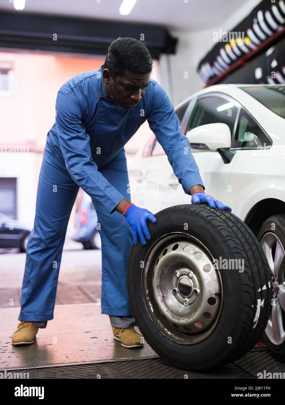 Mechanic engaged in replacement of tyre on car wheel in workshop Stock ...