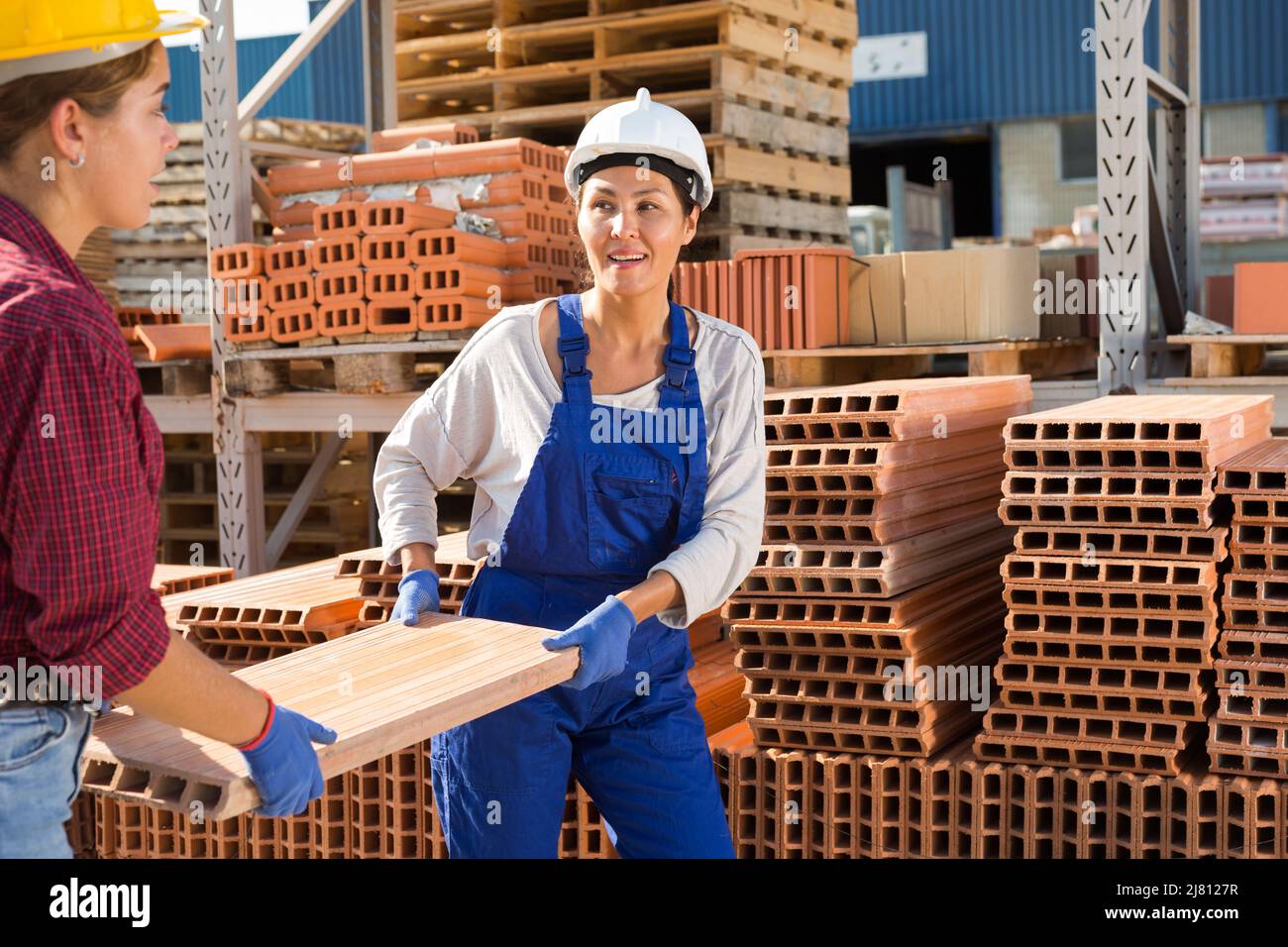 Female workers carrying brick at construction store Stock Photo - Alamy