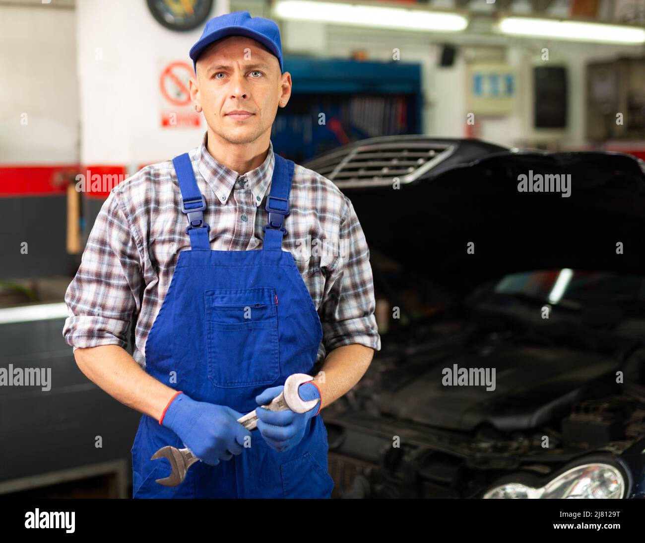 Workman standing near car at auto repair Stock Photo - Alamy