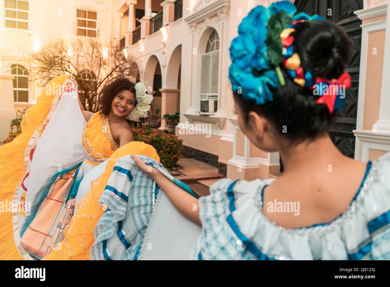 Two young Latina women, one mestizo and one Hispanic, dancing in ...