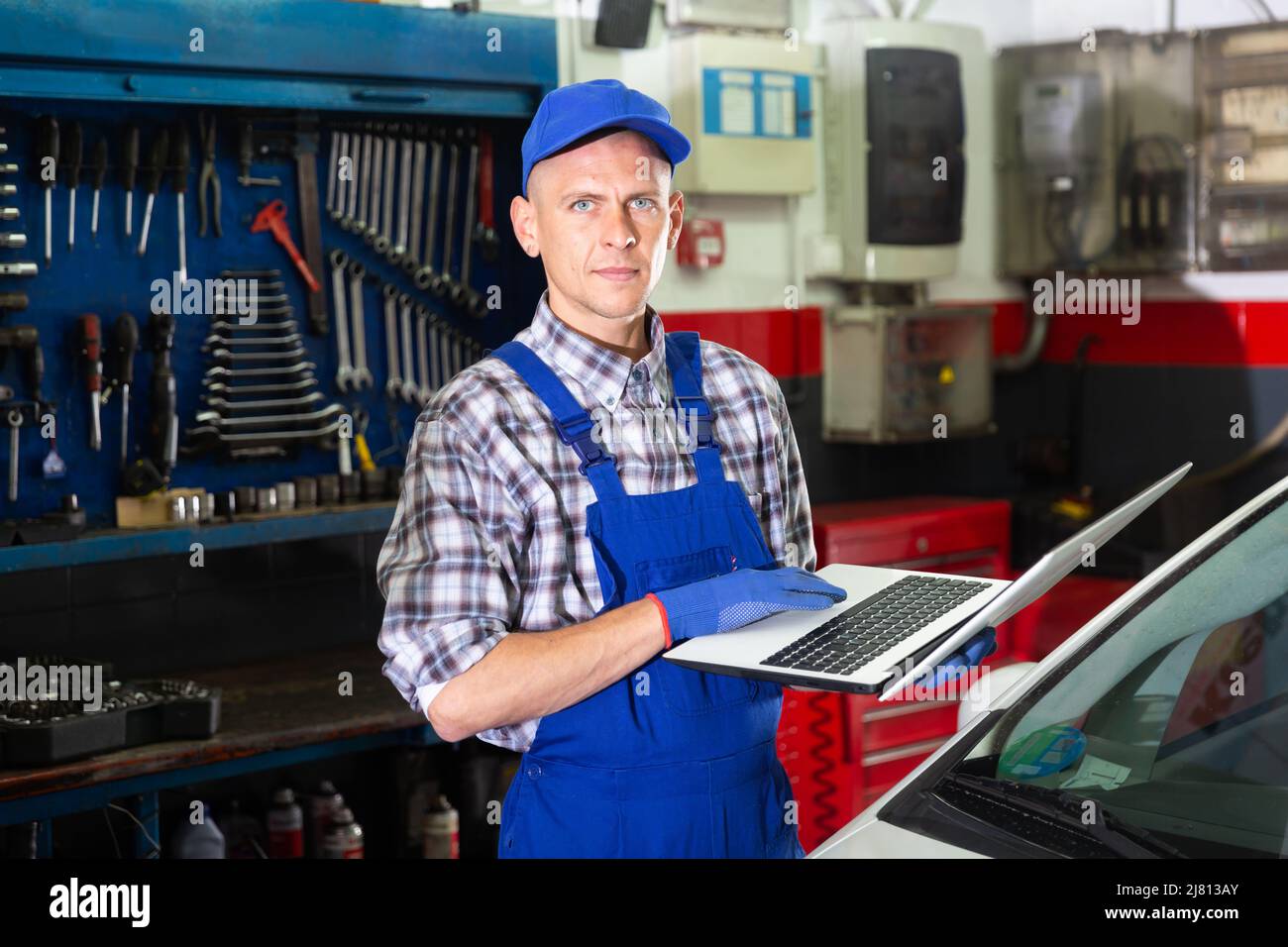 Mechanic with laptop near car engine in auto service Stock Photo - Alamy