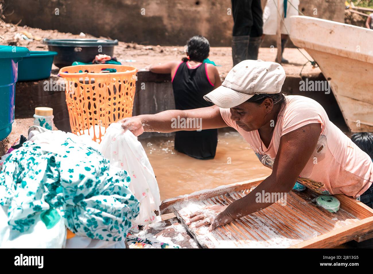 Poor black woman washing clothes in a river in a poor community in the ...