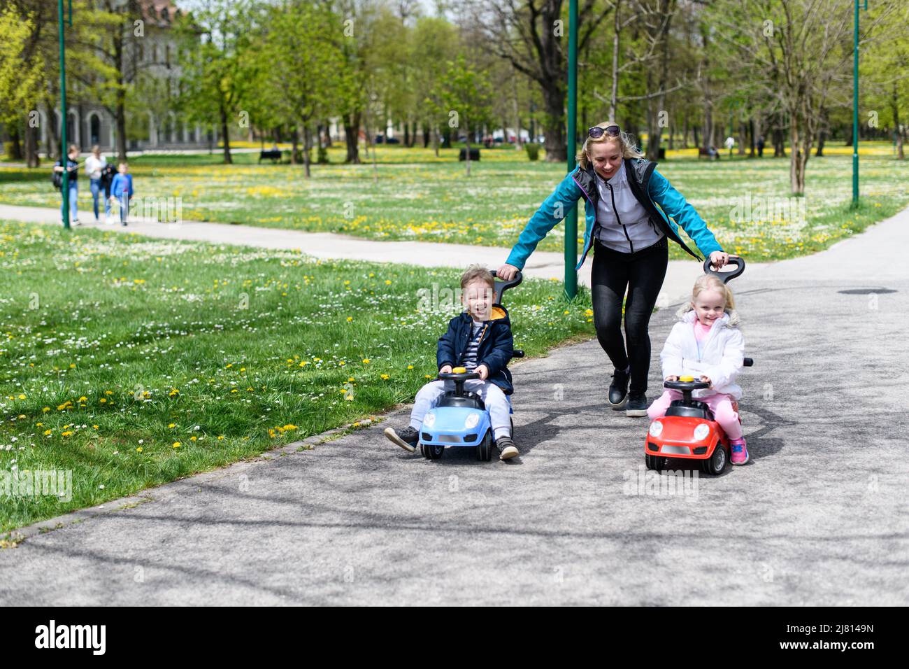 Mom and Kids Are Playing With a Toy Car Outdoors in the Park - A Happy ...