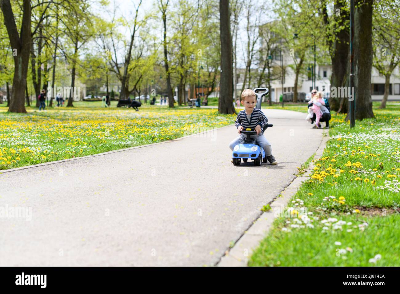 Boy Is Playing With a Toy Car Outdoors in the Park - A Happy Boy Rides in a Blue Toy Car on the ...