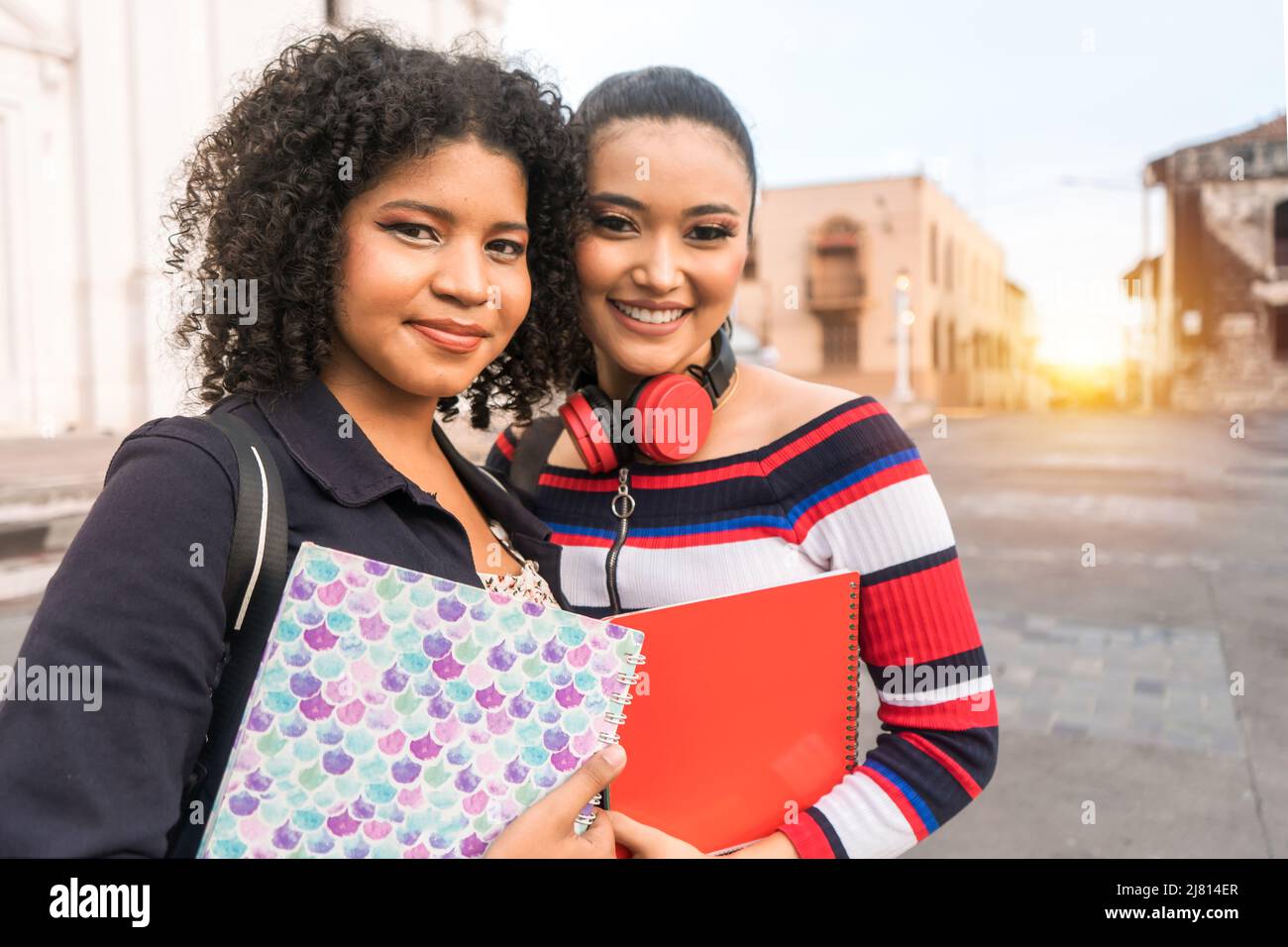 Two multiracial Latina students looking at the camera and smiling in ...