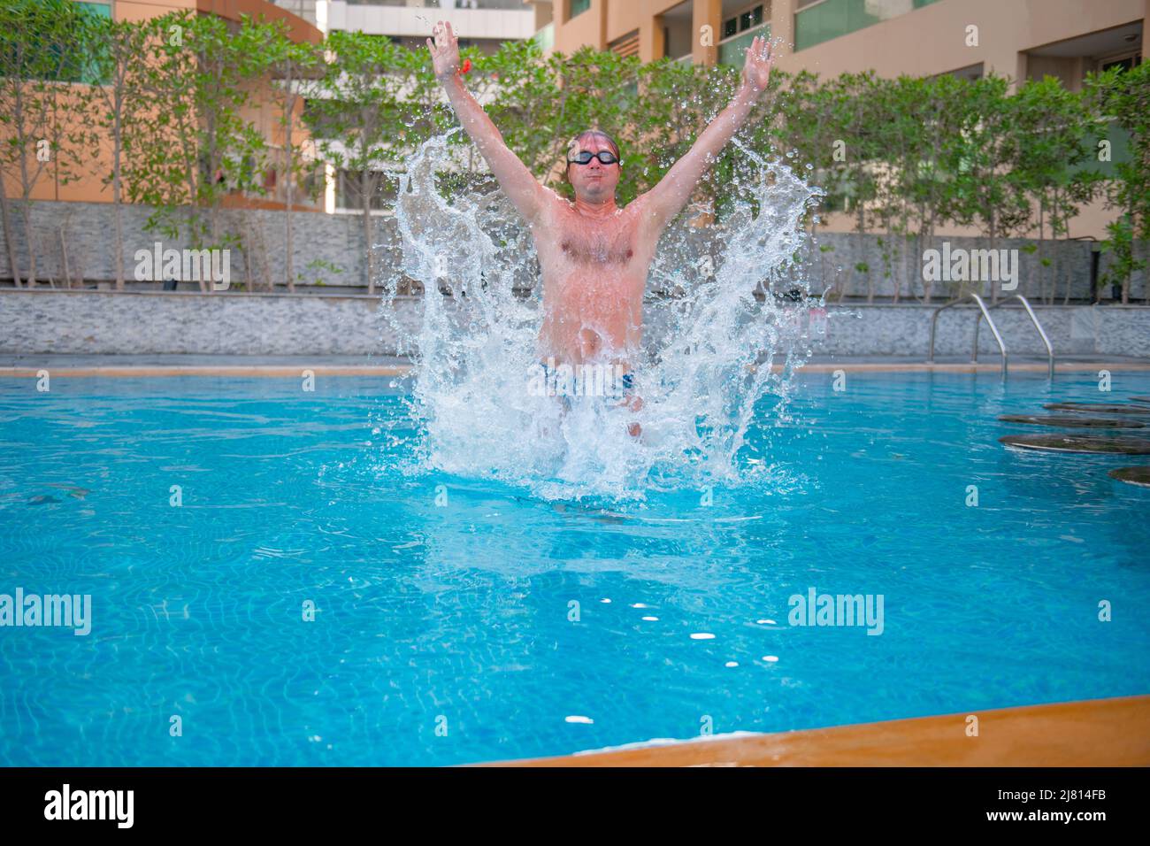 in swimming trunks a man jumps up in a large pool Stock Photo - Alamy
