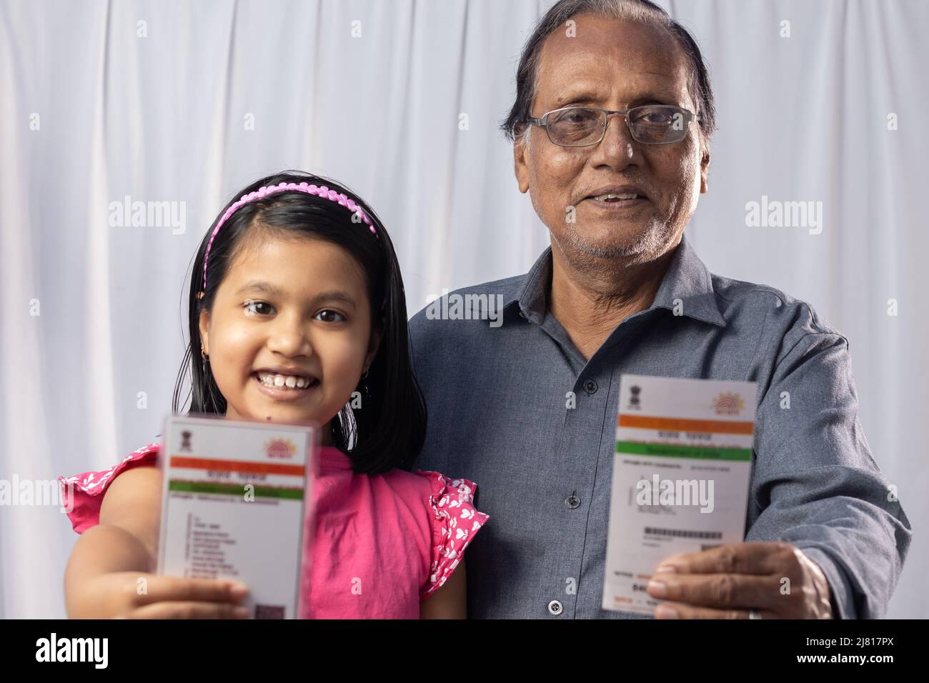 An Indian old man with his grand daughter smiling with Aadhaar card in ...