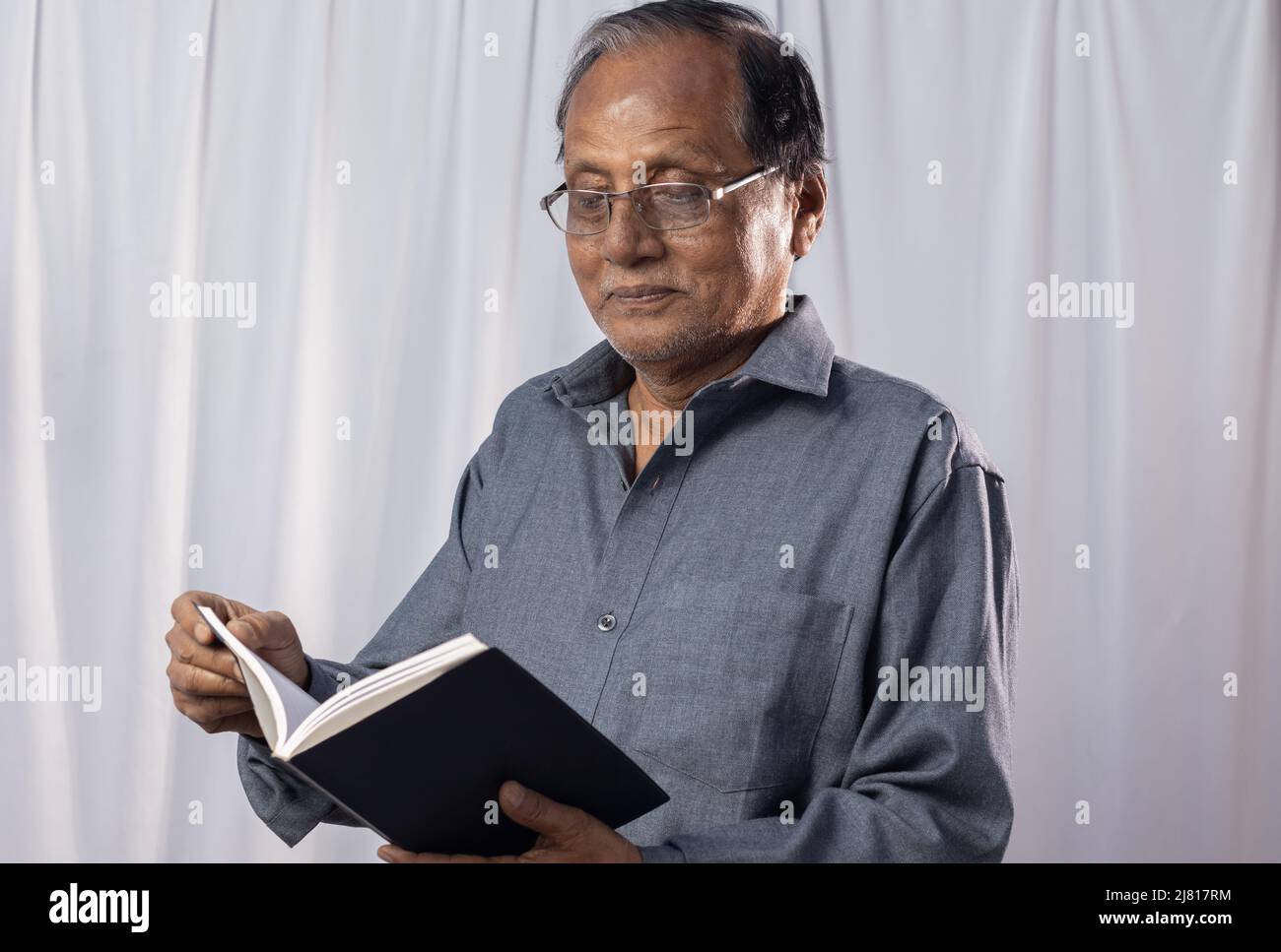 An old Indian man is reading books standing on white background Stock ...